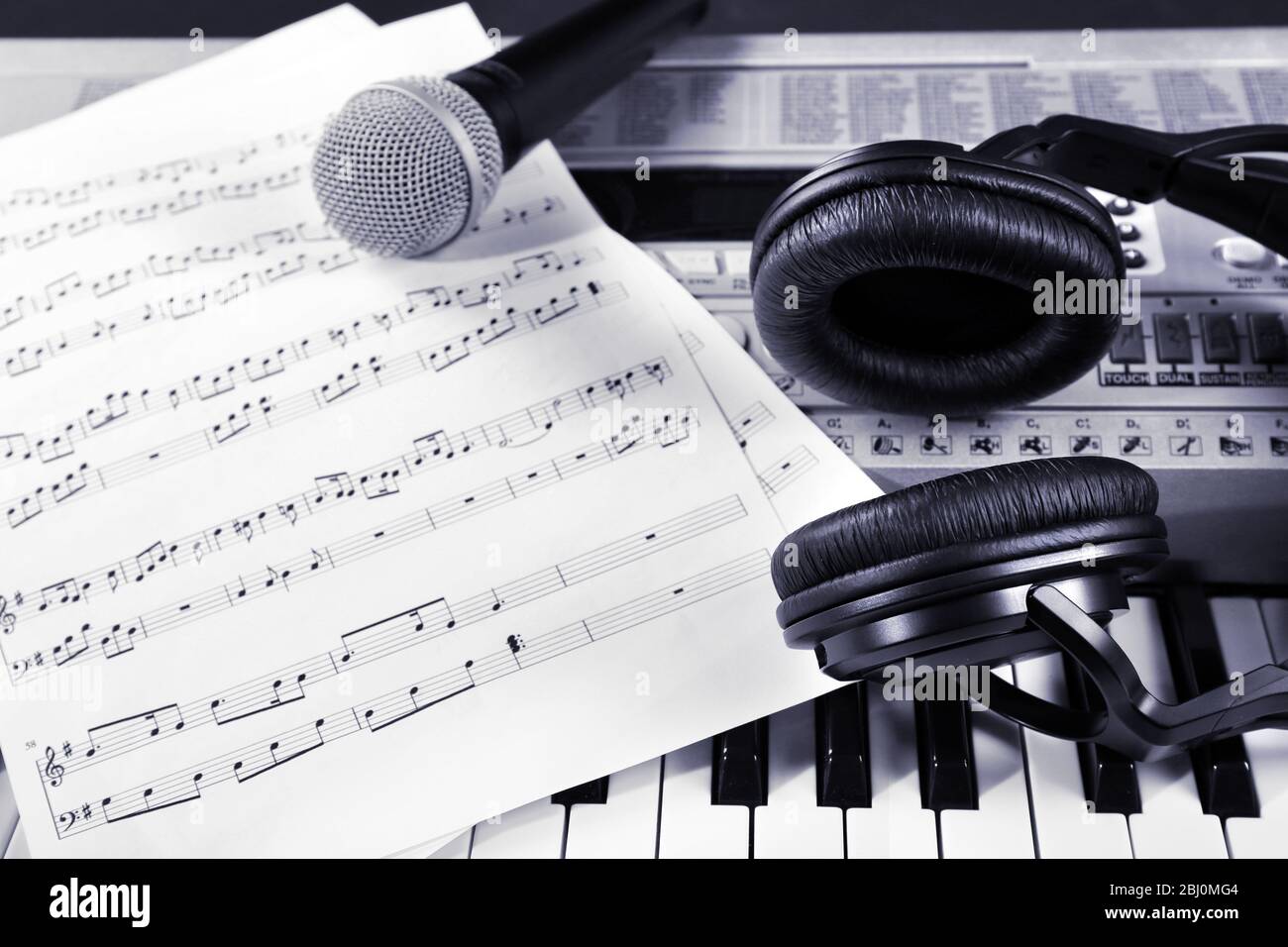 Headphones with music notes and microphone on synthesizer close up ...