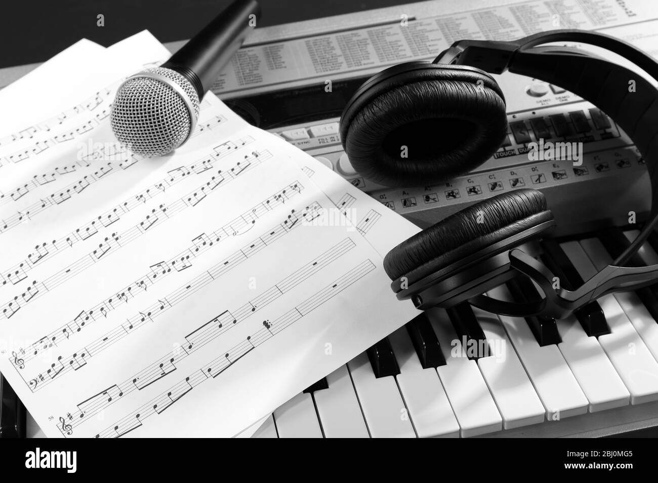 Headphones with music notes and microphone on synthesizer close up ...