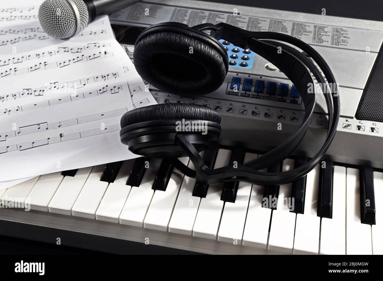 Headphones with music notes and microphone on synthesizer close up ...