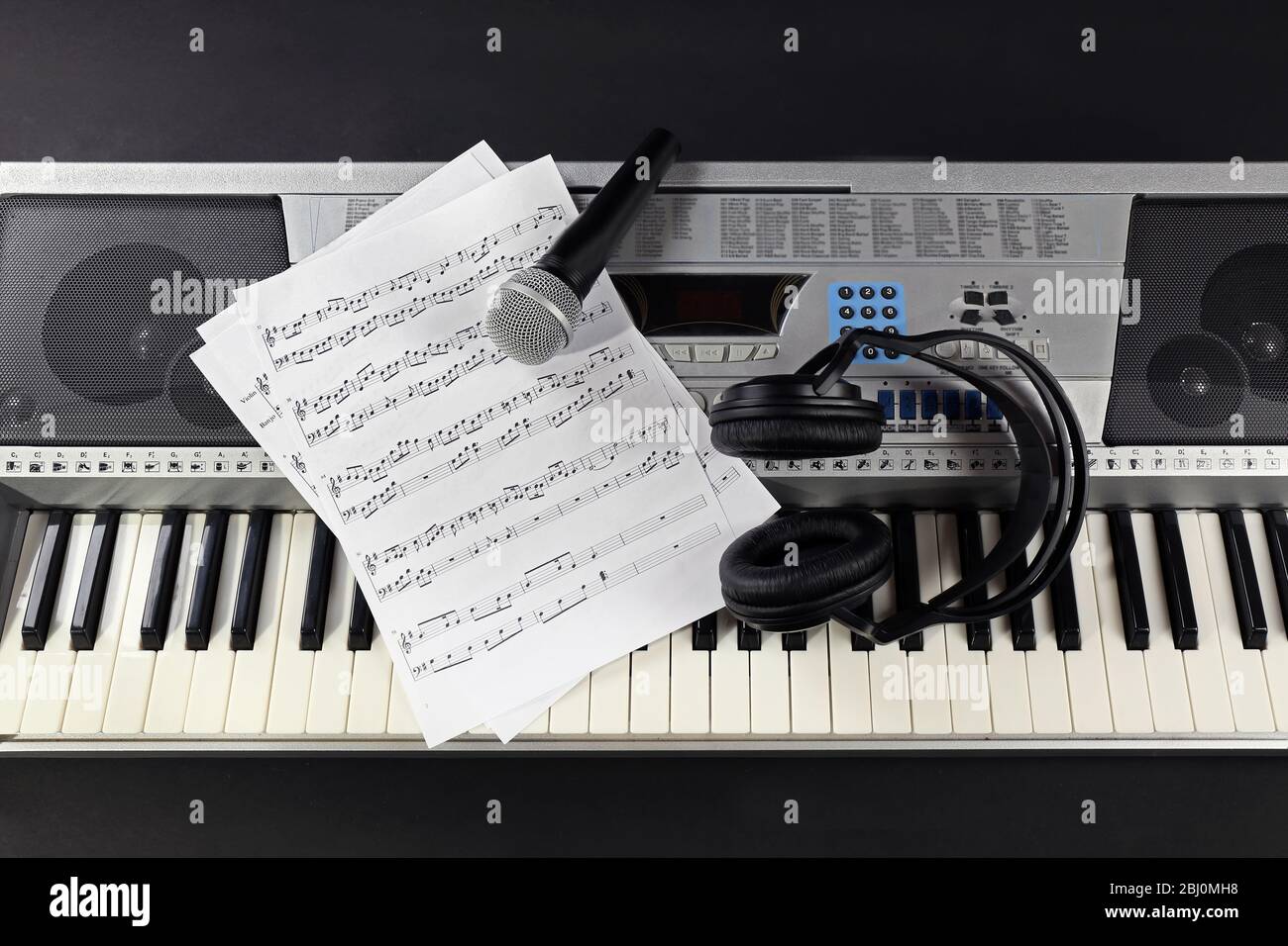 Headphones with music notes and microphone on synthesizer close up ...