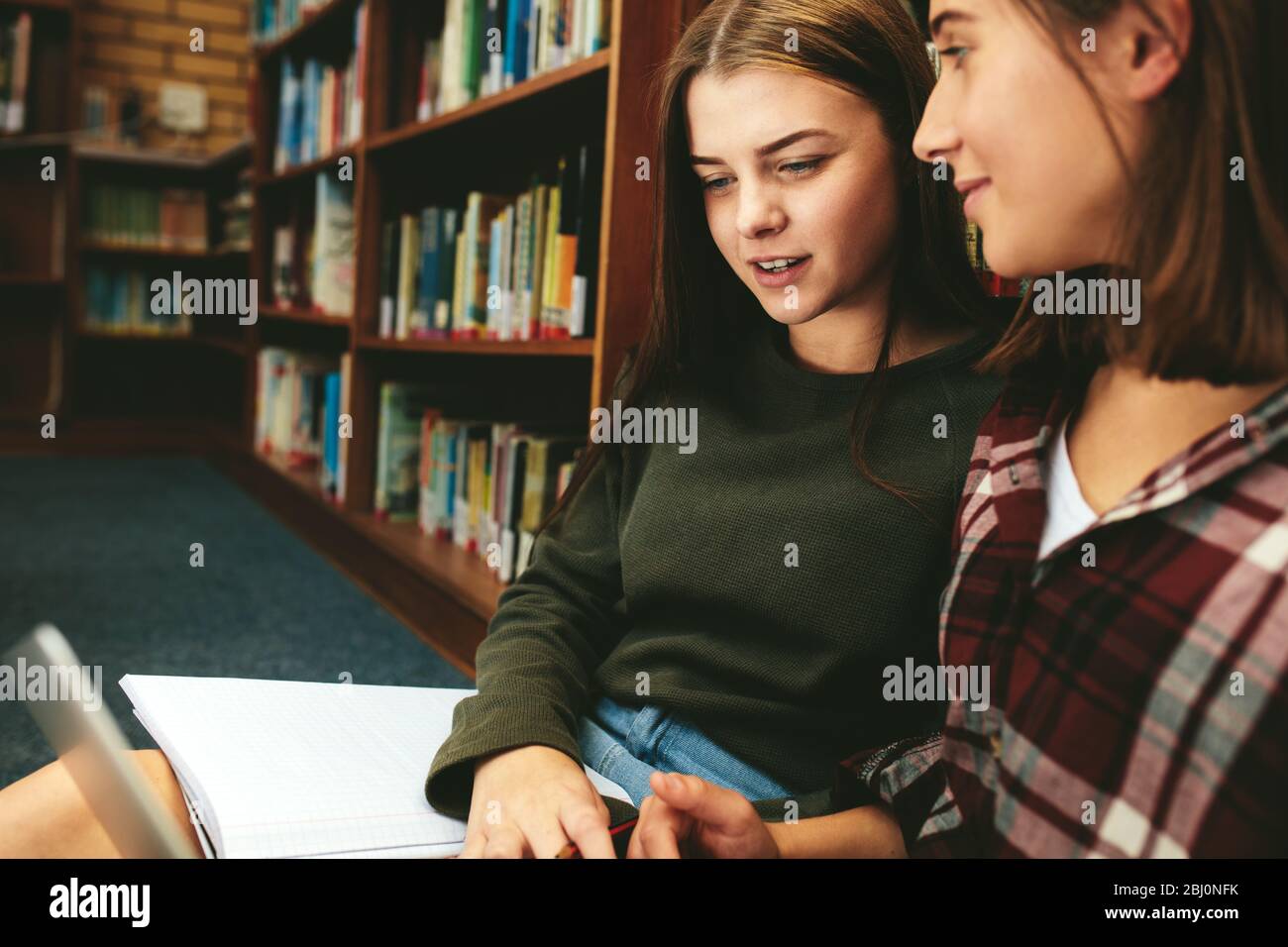 Female students studying in the library. Young people sitting together ...