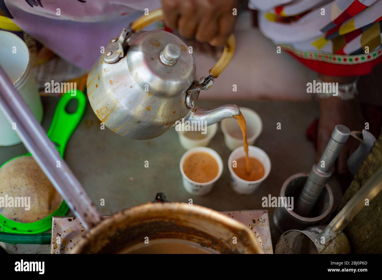 Tea pot serving tea in four plastic cups at a roadside tea stall ...