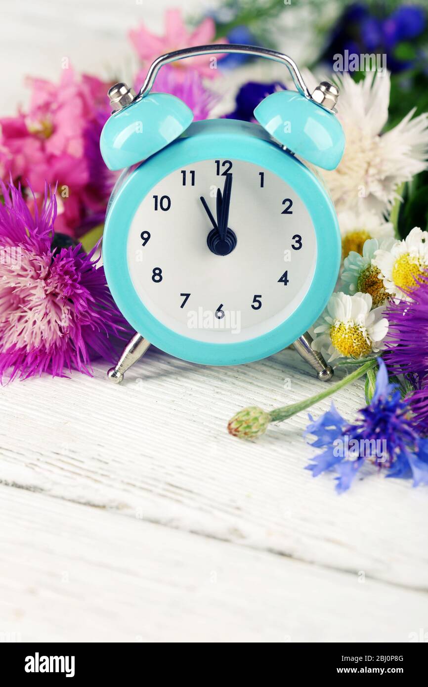 Small alarm clock with beautiful flowers on table close up Stock Photo ...