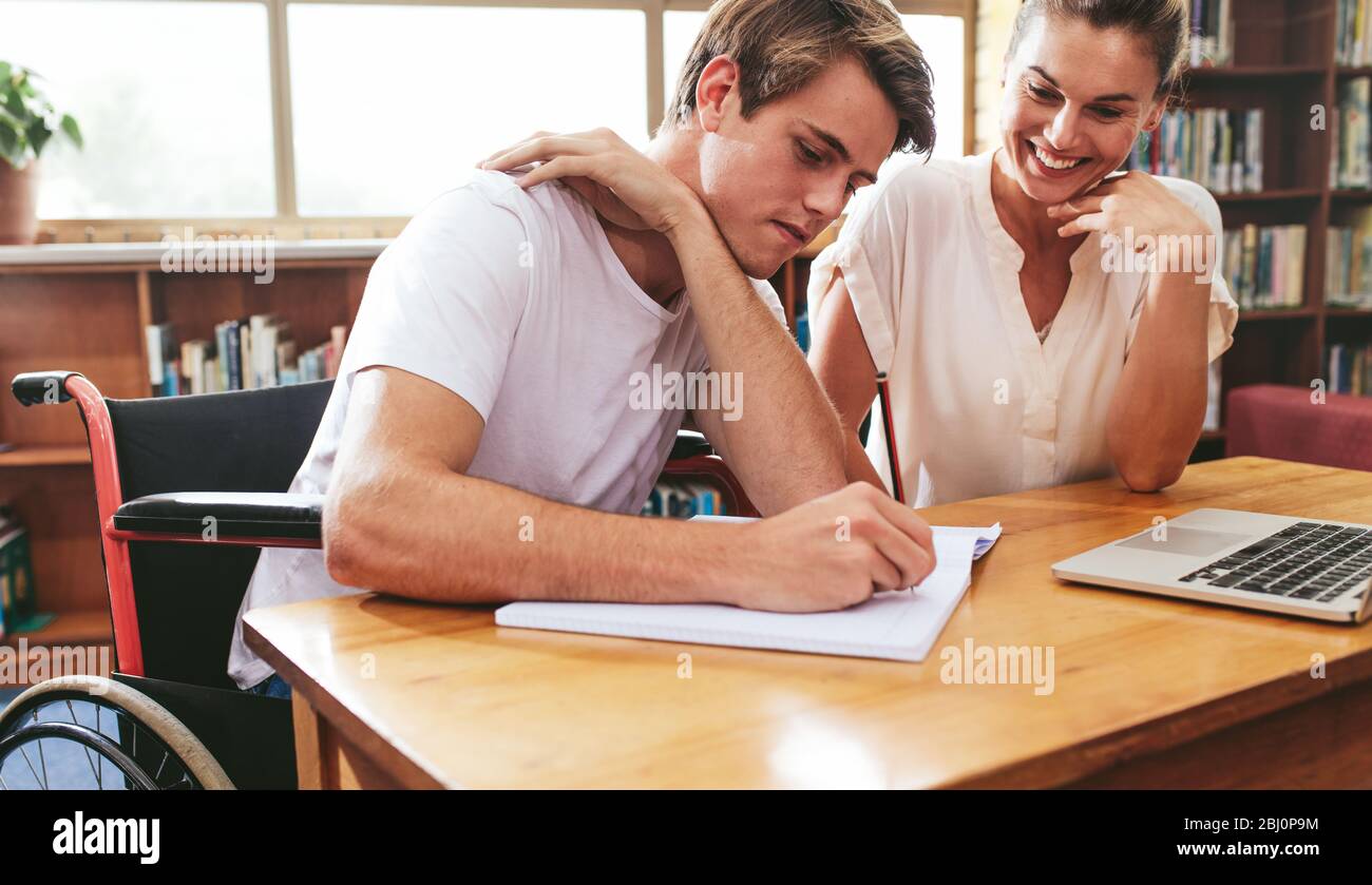 Disabled student studying with teacher in classroom. Teenage boy ...