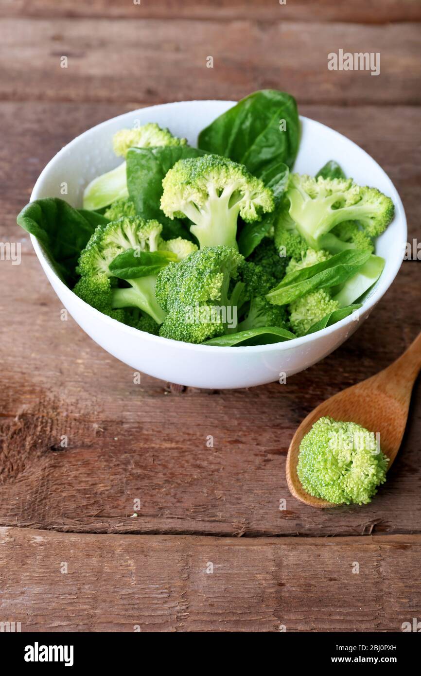 Fresh broccoli with spinach in bowl on wooden table close up Stock ...