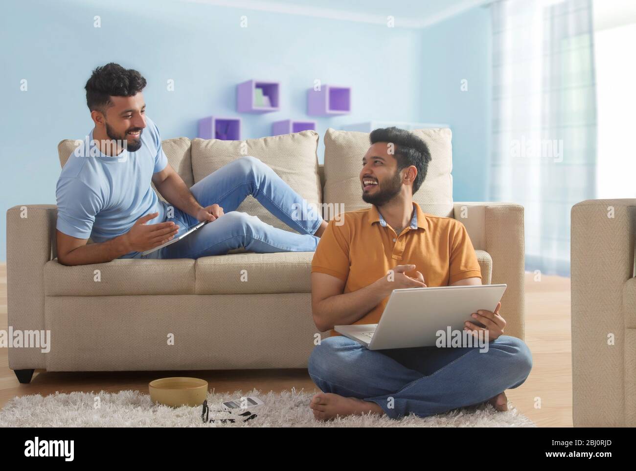 Roommates sitting and enjoying in the living room at home Stock Photo ...