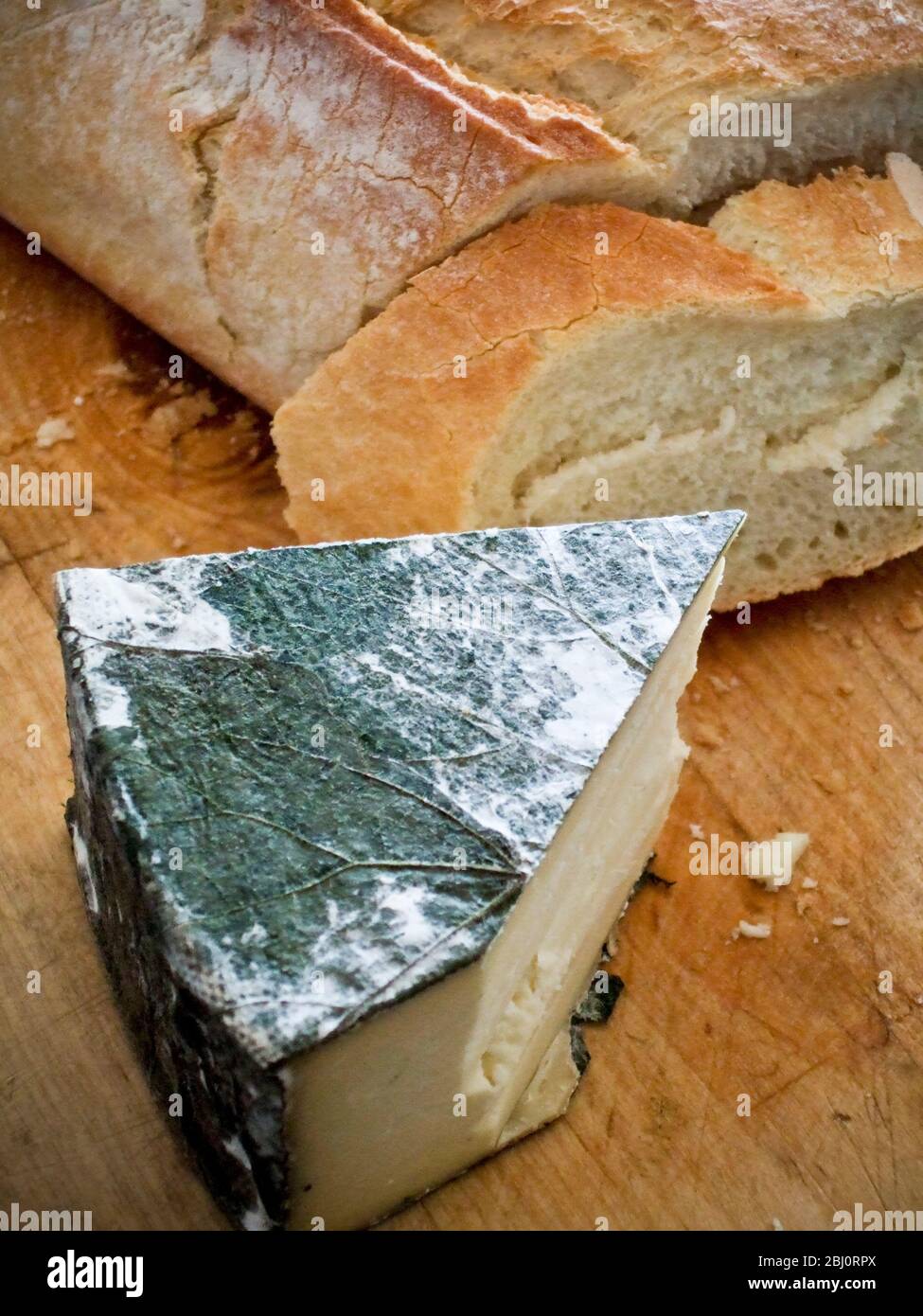 Cornish Yarg cheese with covering of nettles on board with crusty bread ...