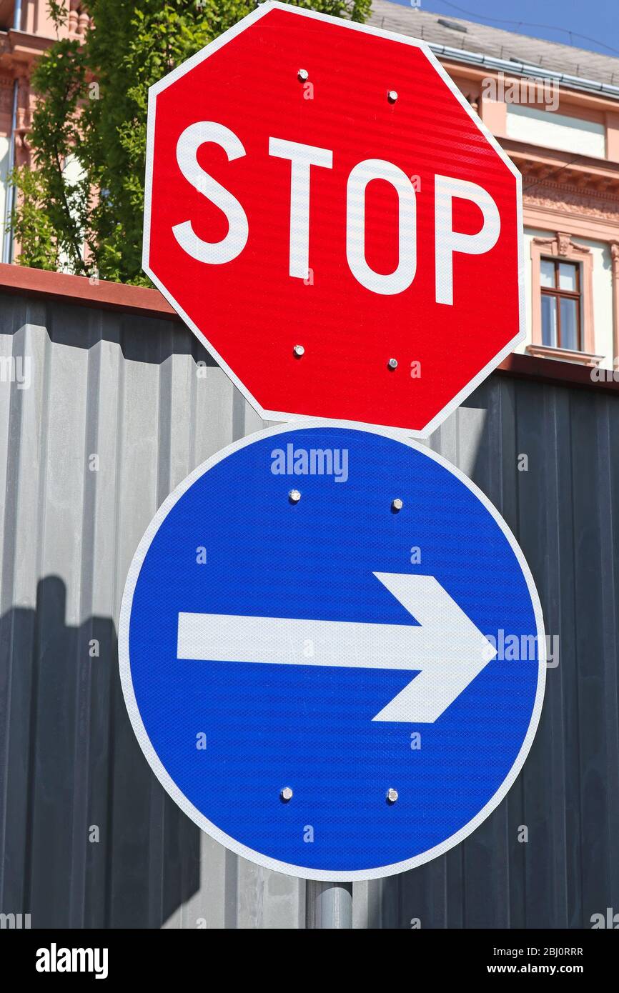 Stop sign and arrow sign at the road crossing Stock Photo - Alamy