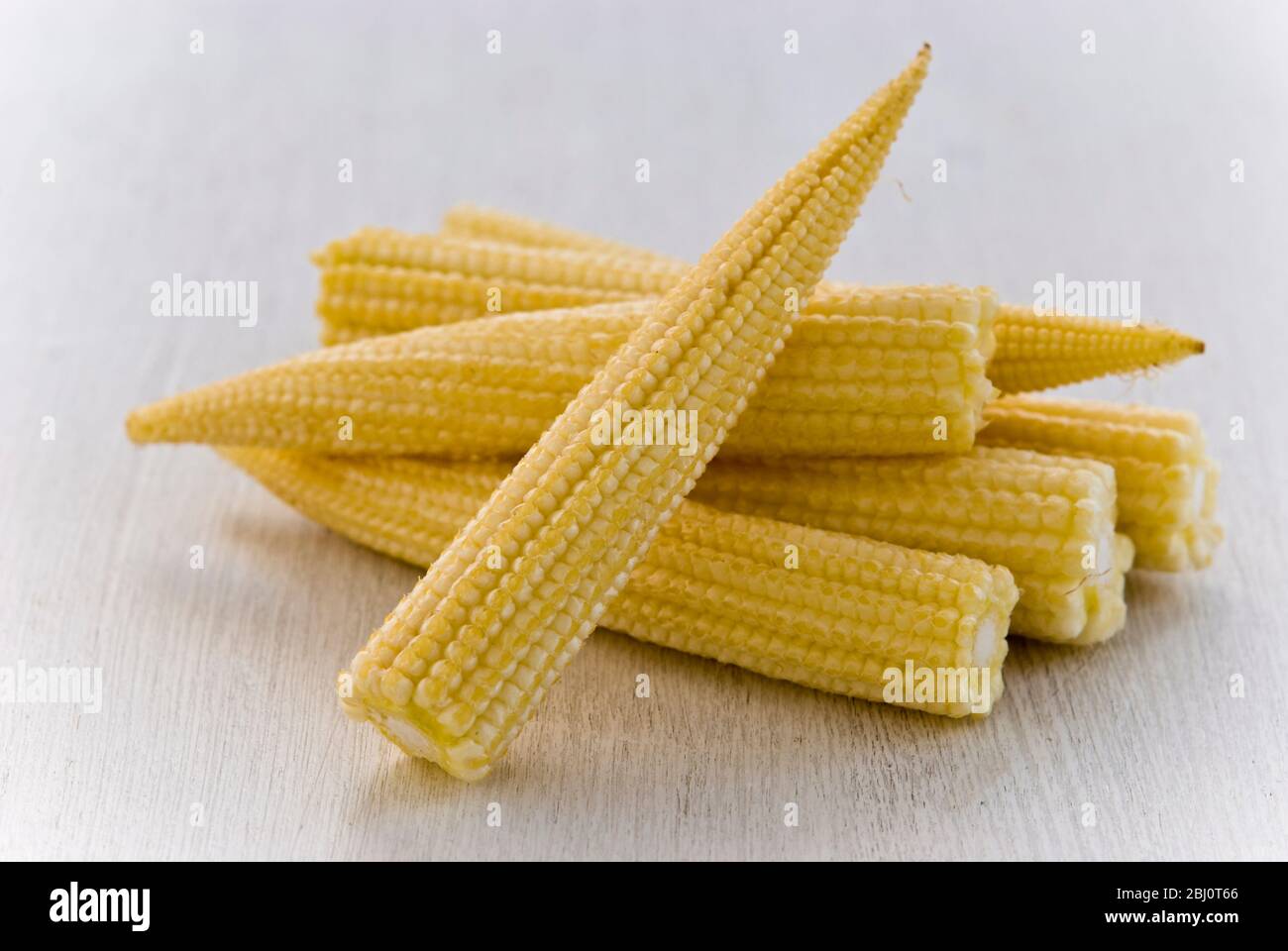 Small pile of baby sweetcorn on white background Stock Photo - Alamy