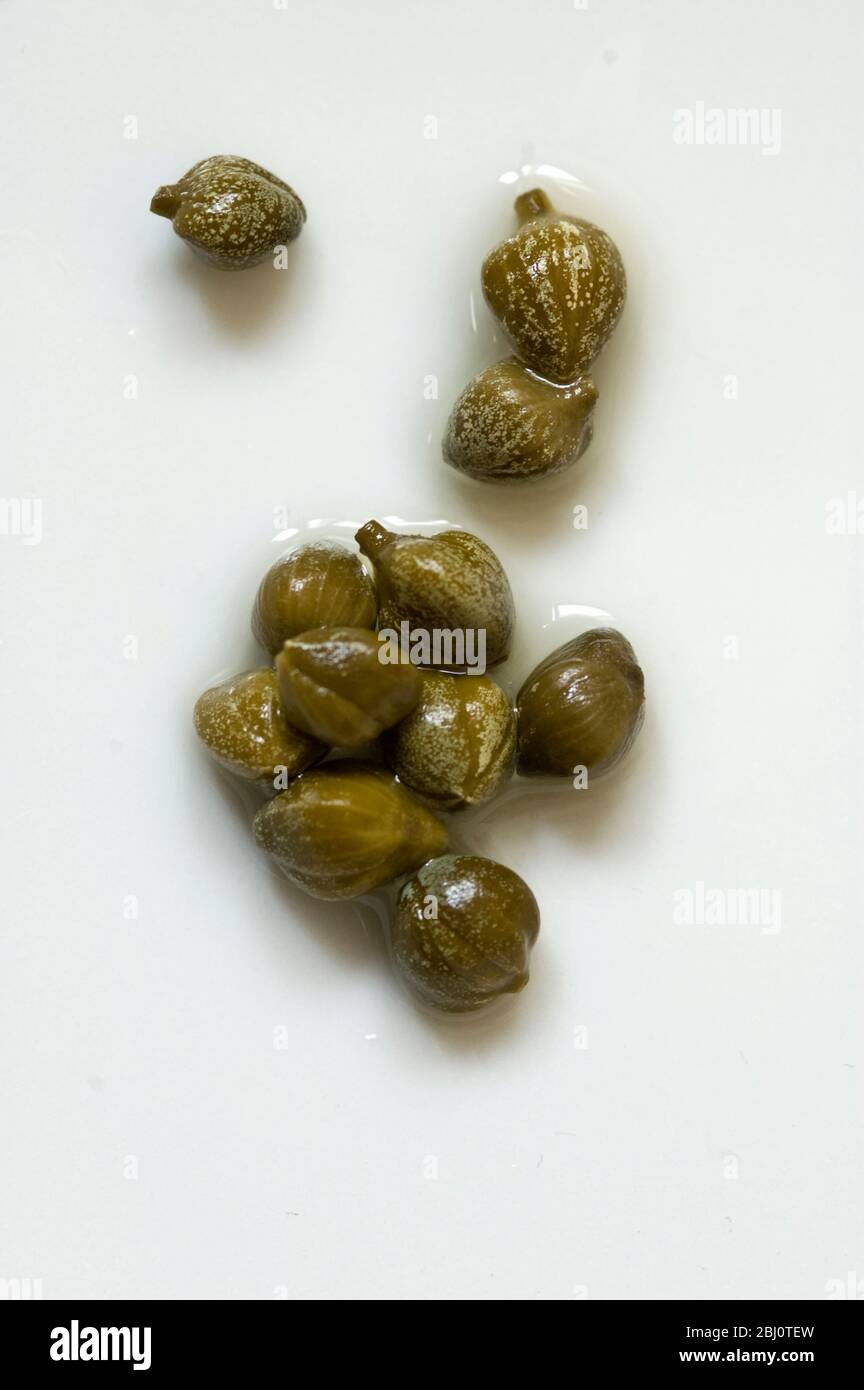 Nonpareille capers on white surface Stock Photo - Alamy
