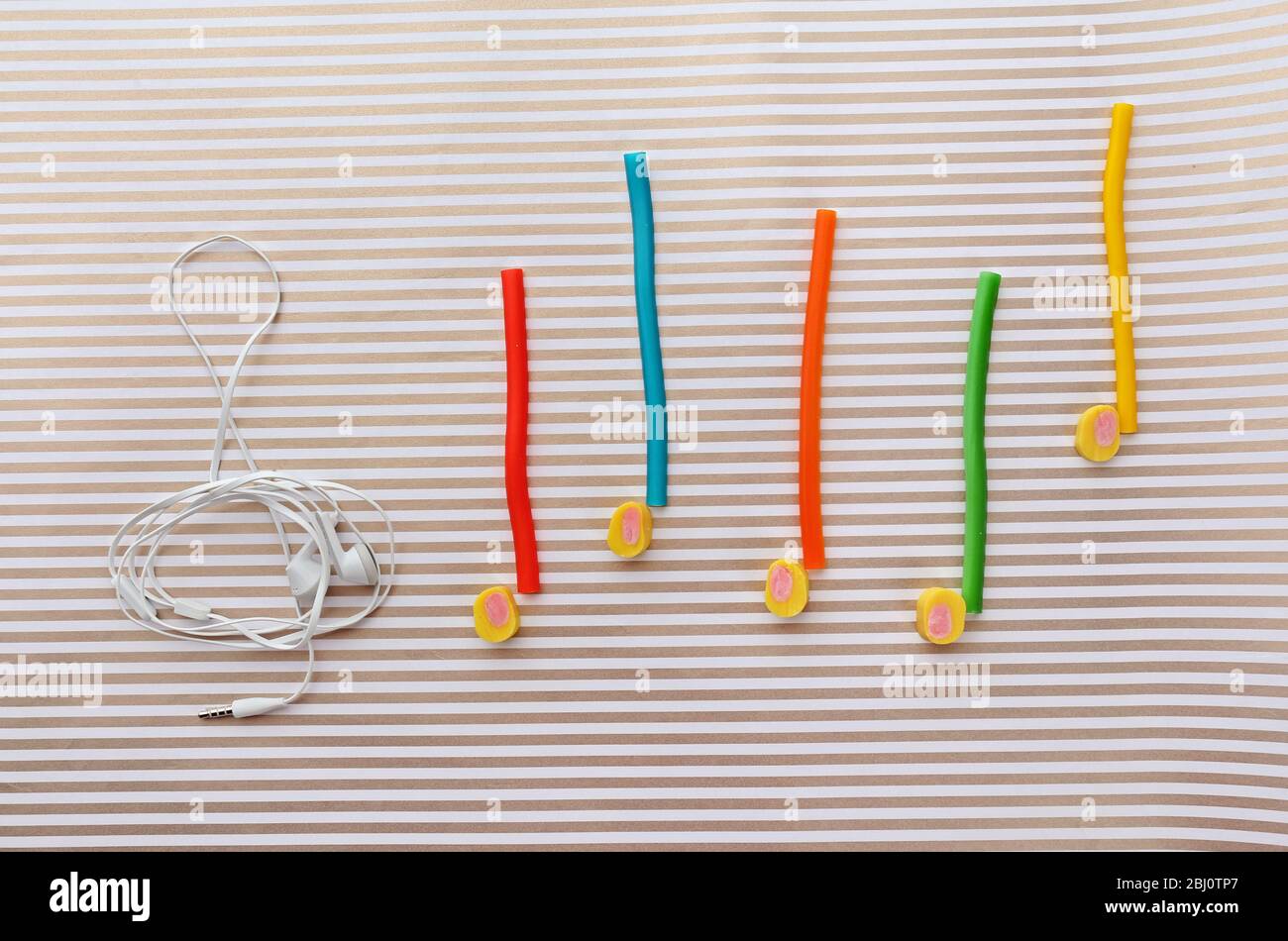 Treble clef with musical notes of candies and headphones on striped ...