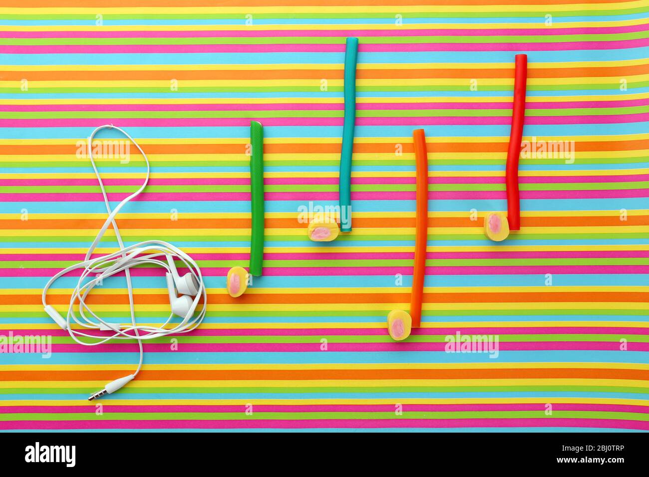 Treble clef with musical notes of candies and headphones on striped ...