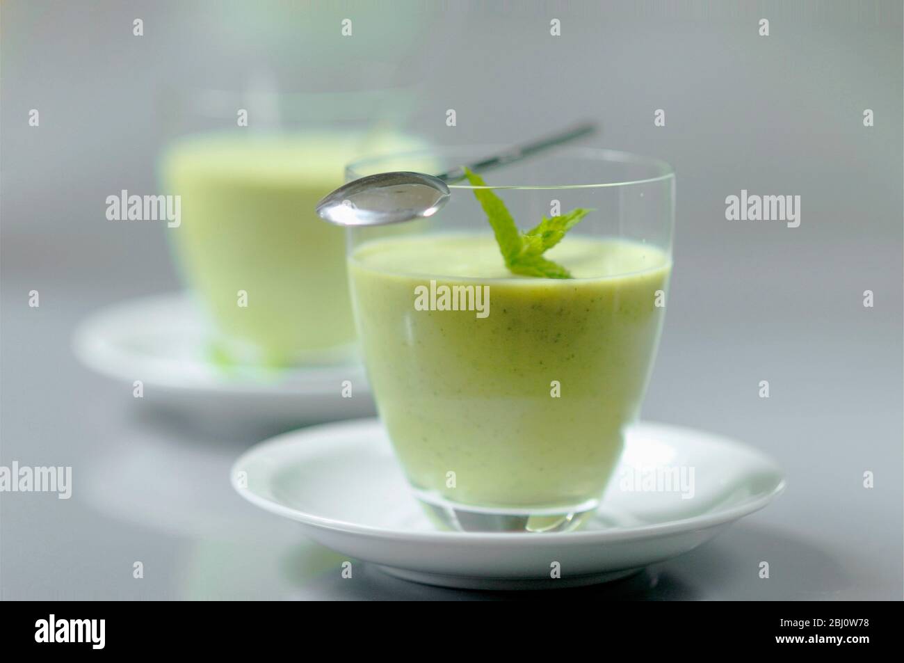 Chilled soup of fresh garden peas and courgettes in small glasses on ...