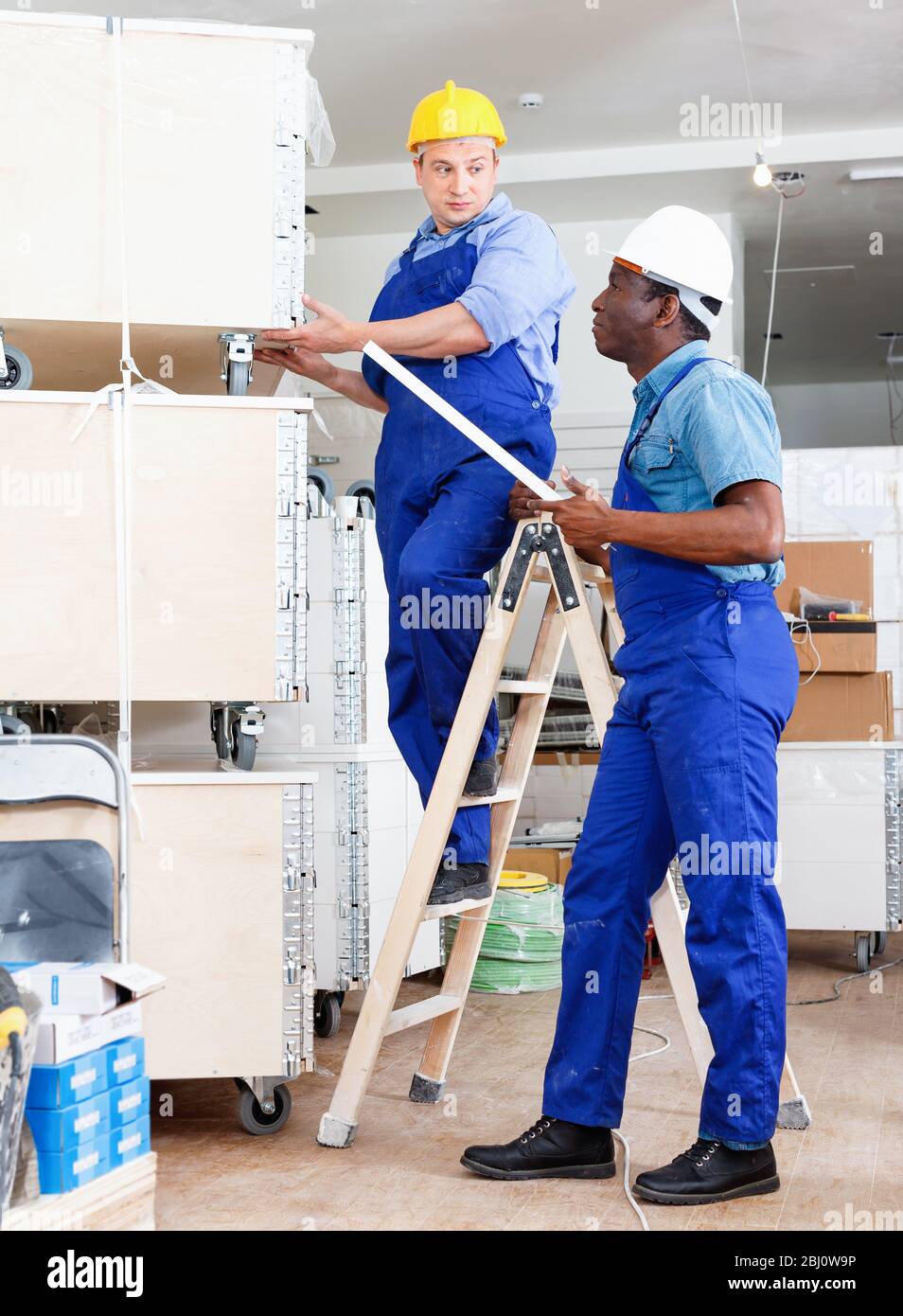 Two efficient positive friendly male builders working at indoors ...