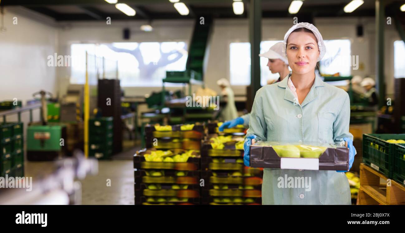 Young happy cheerful positive woman in uniform during sorting at ...