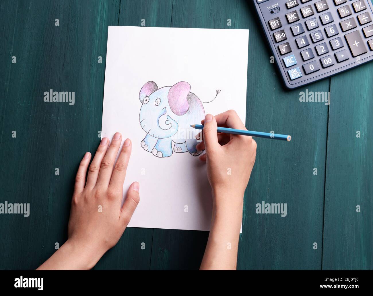 Female hands drawing picture on sheet of paper on wooden table ...