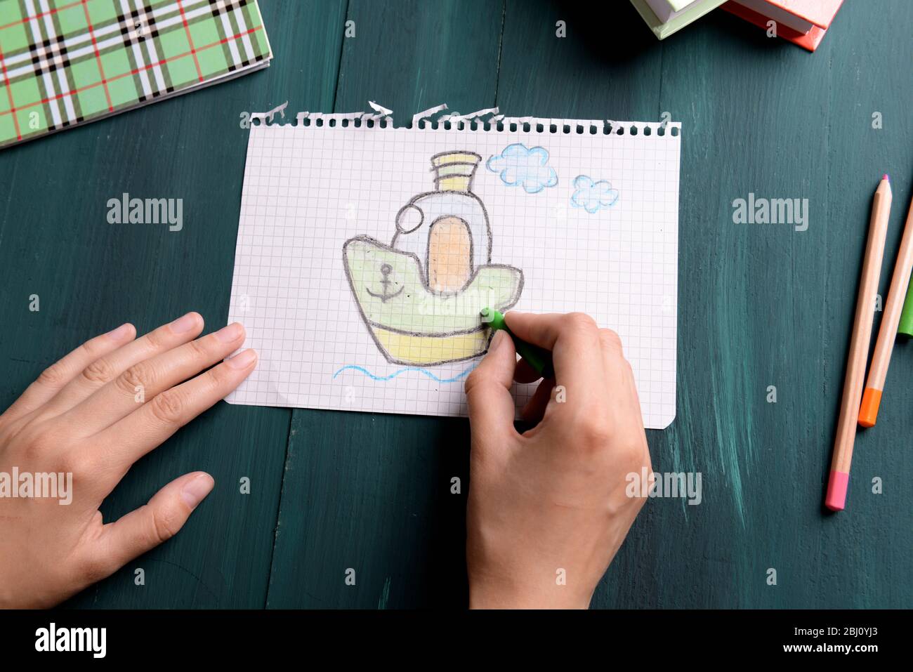Female hands drawing picture on sheet of paper on wooden table ...