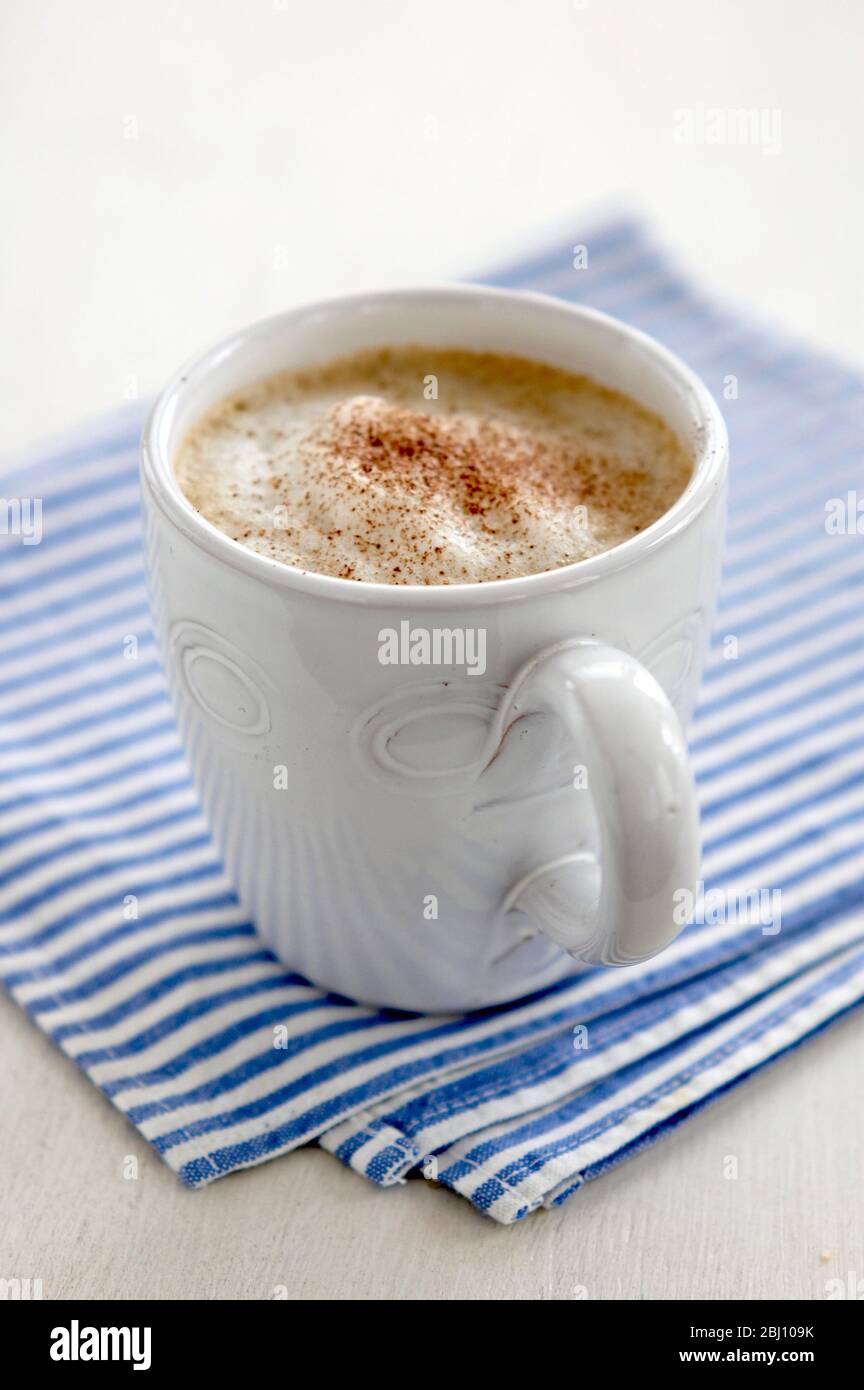 White china mug of cappucino coffee with frothy topping and sprinkled ...