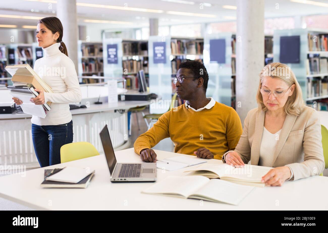 Teacher and adult students talking in the library Stock Photo - Alamy