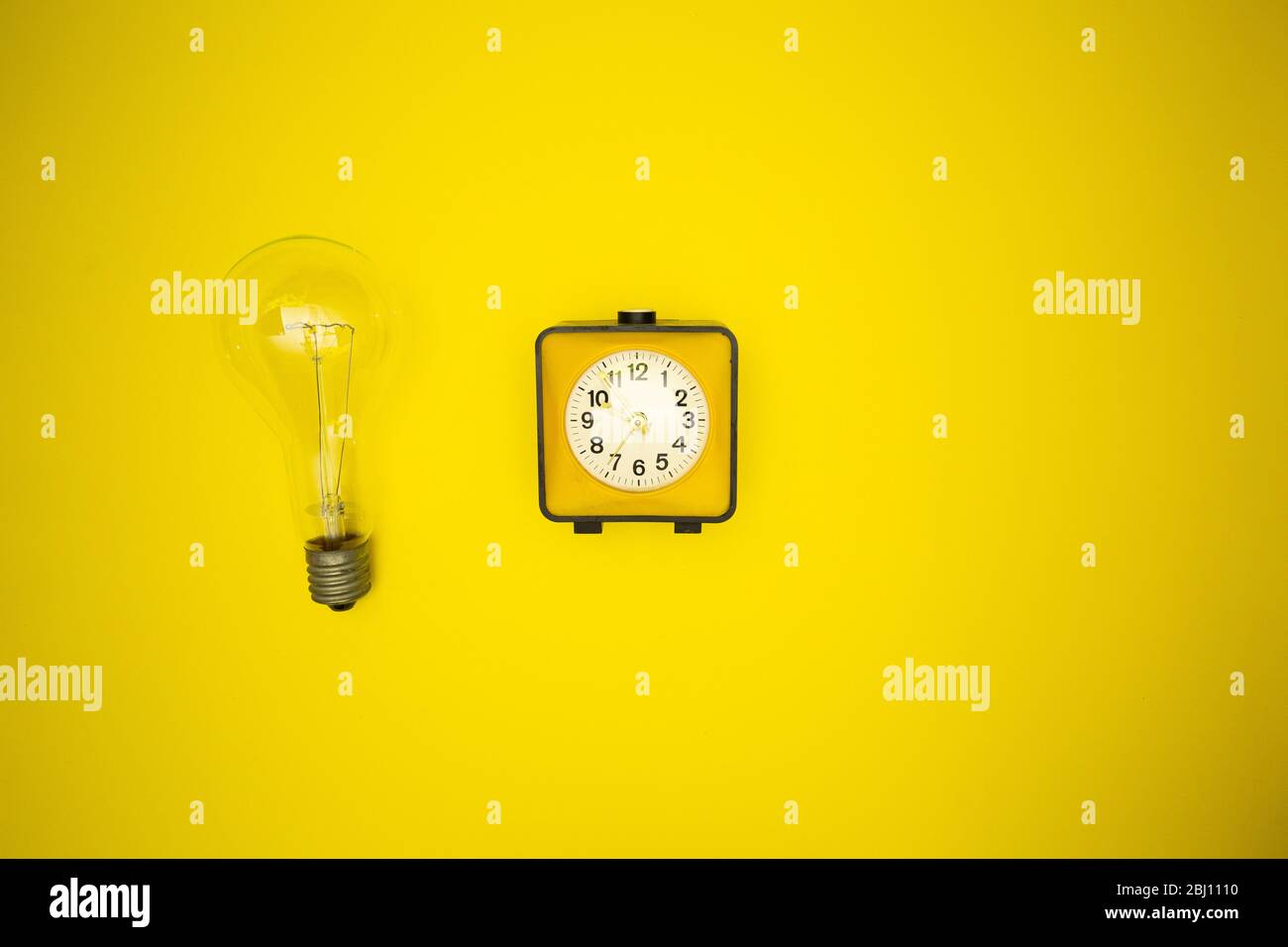 Yellow alarm clock and light bulb Stock Photo - Alamy