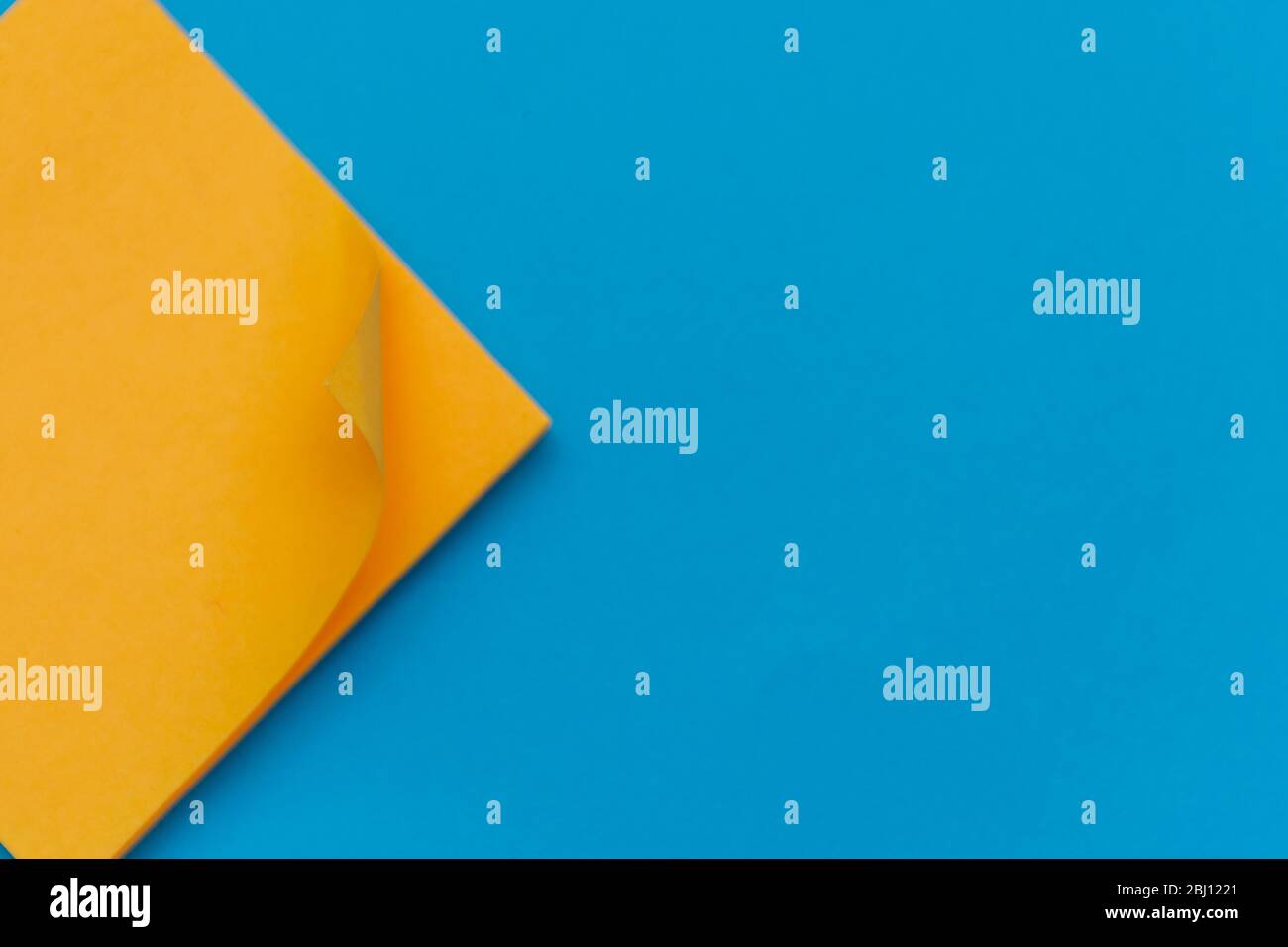 Bright orange posted note on bright blue flat lay background for ...