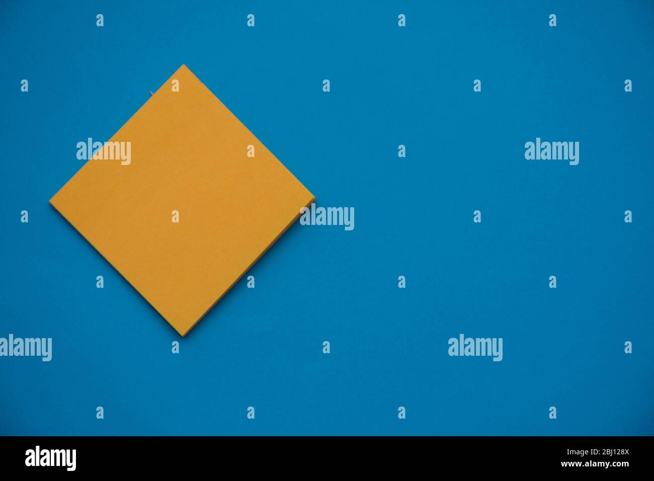 Bright orange posted note on bright blue flat lay background for ...