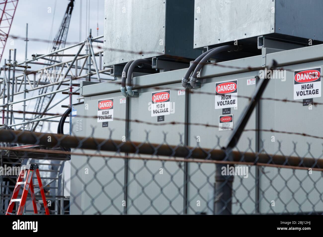 Power grid substation with high voltage warning signs behind a barbed ...