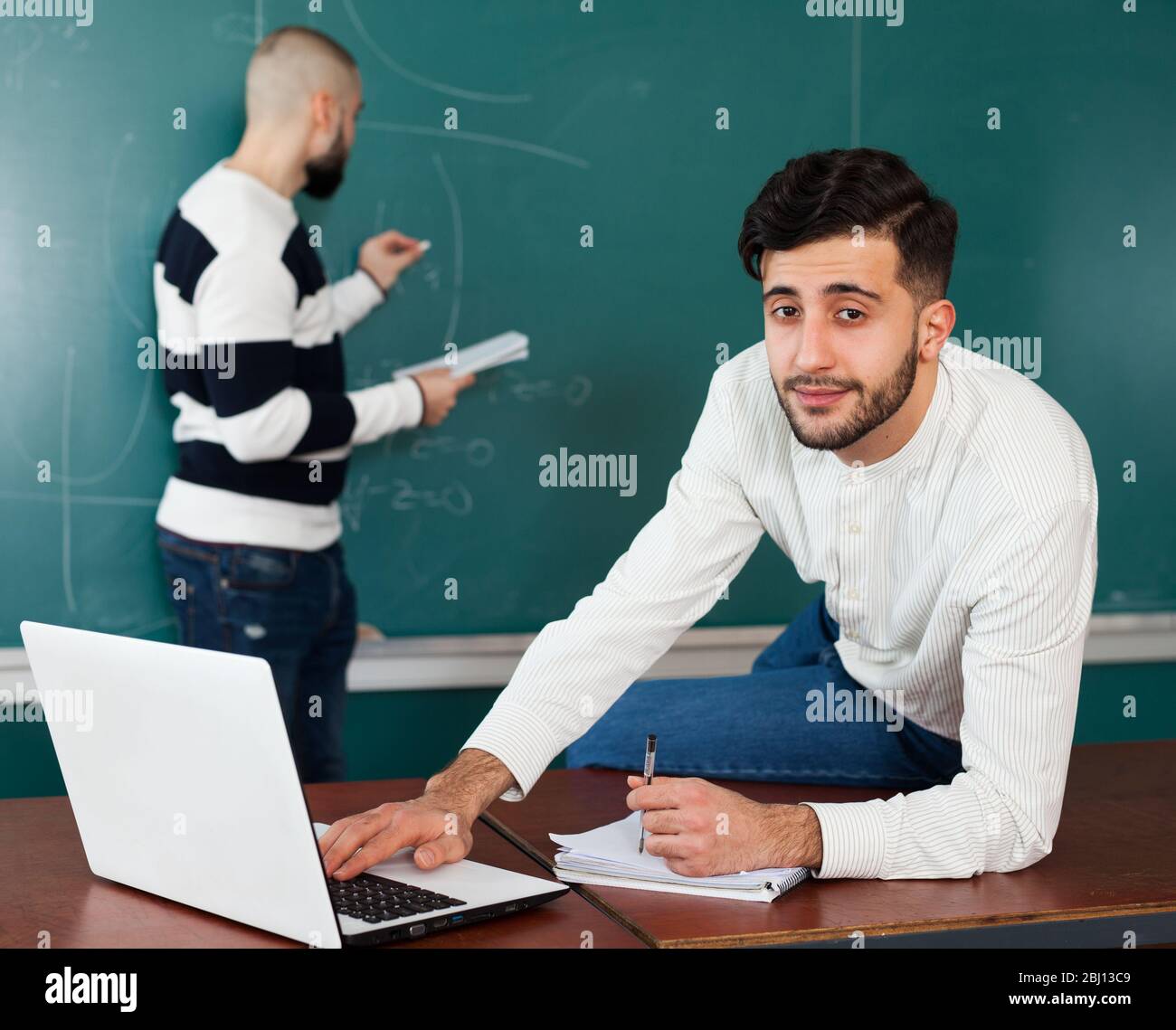 Portrait of two young guys working on their student project near ...