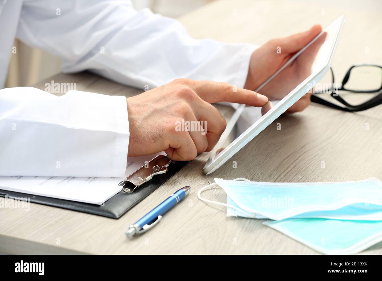 Doctor working at table in office Stock Photo - Alamy