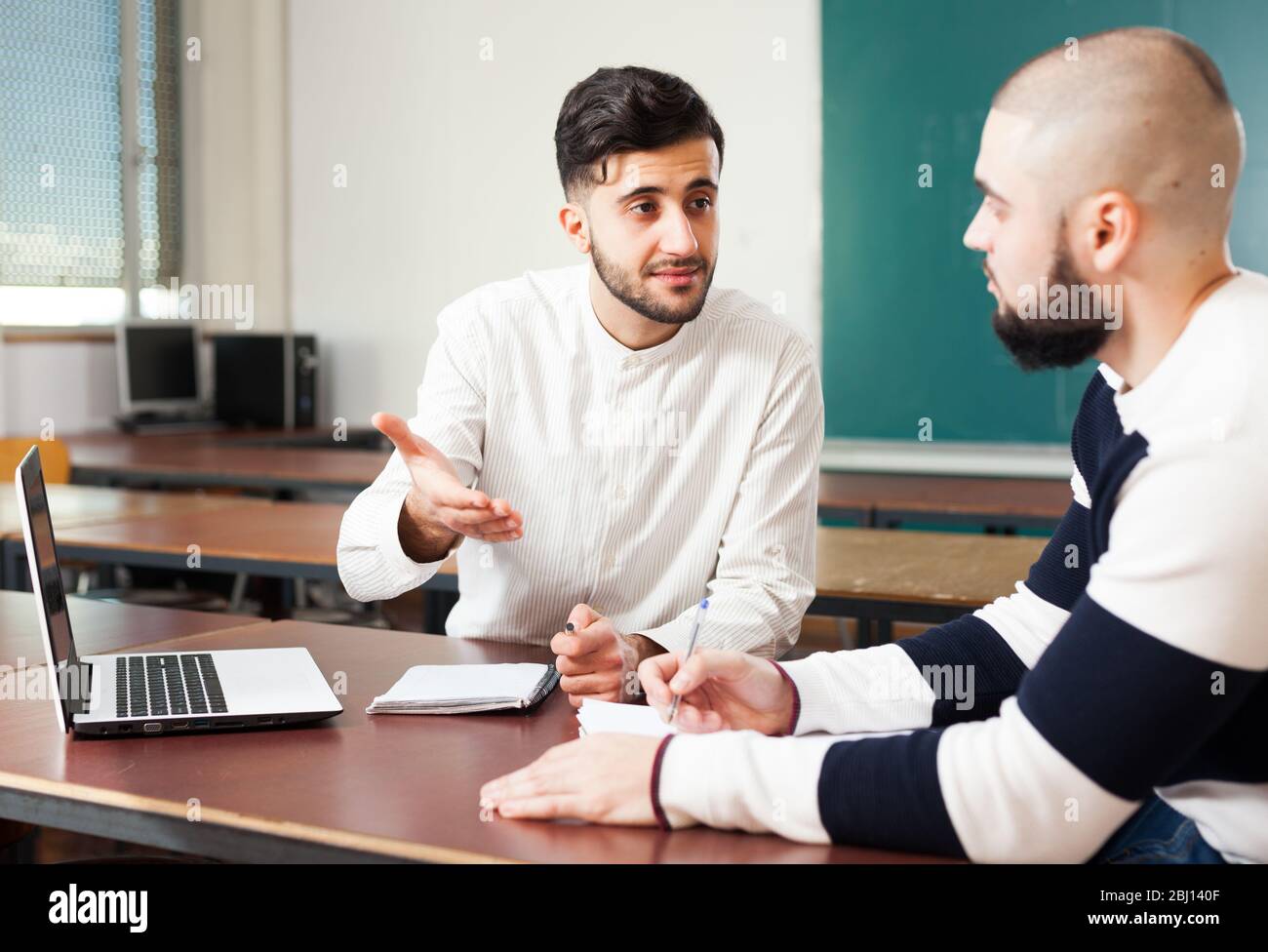 Portrait of two young guys working on their student project at desk in ...