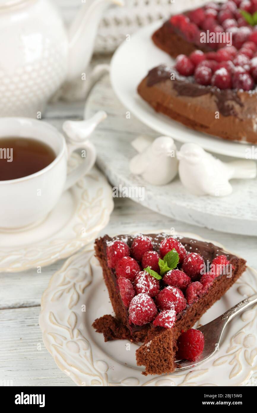 Piece of cake with chocolate Glaze and raspberries on color wooden ...