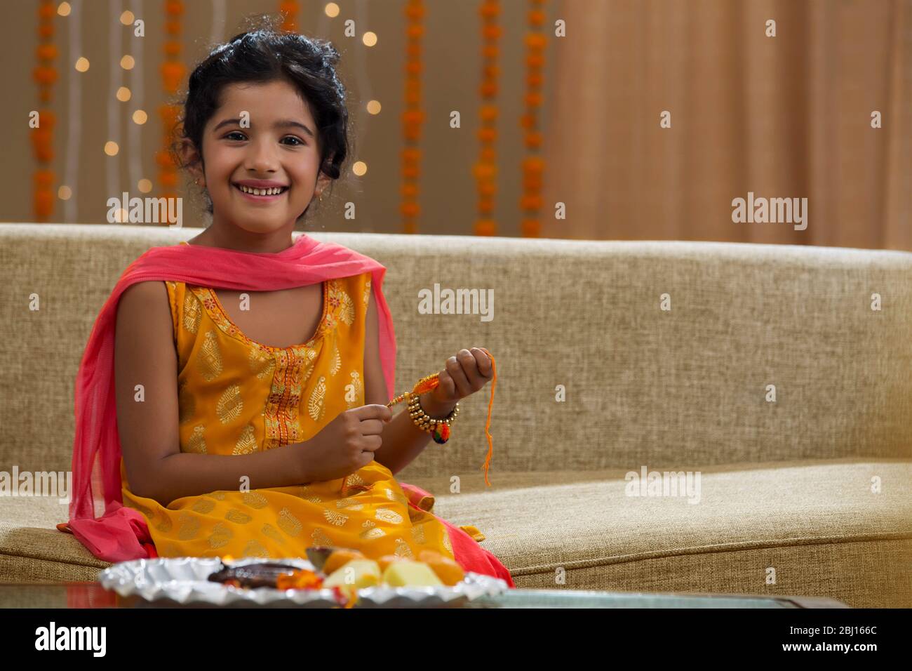 Cute girl smiling with a Rakhi in her hand Stock Photo - Alamy
