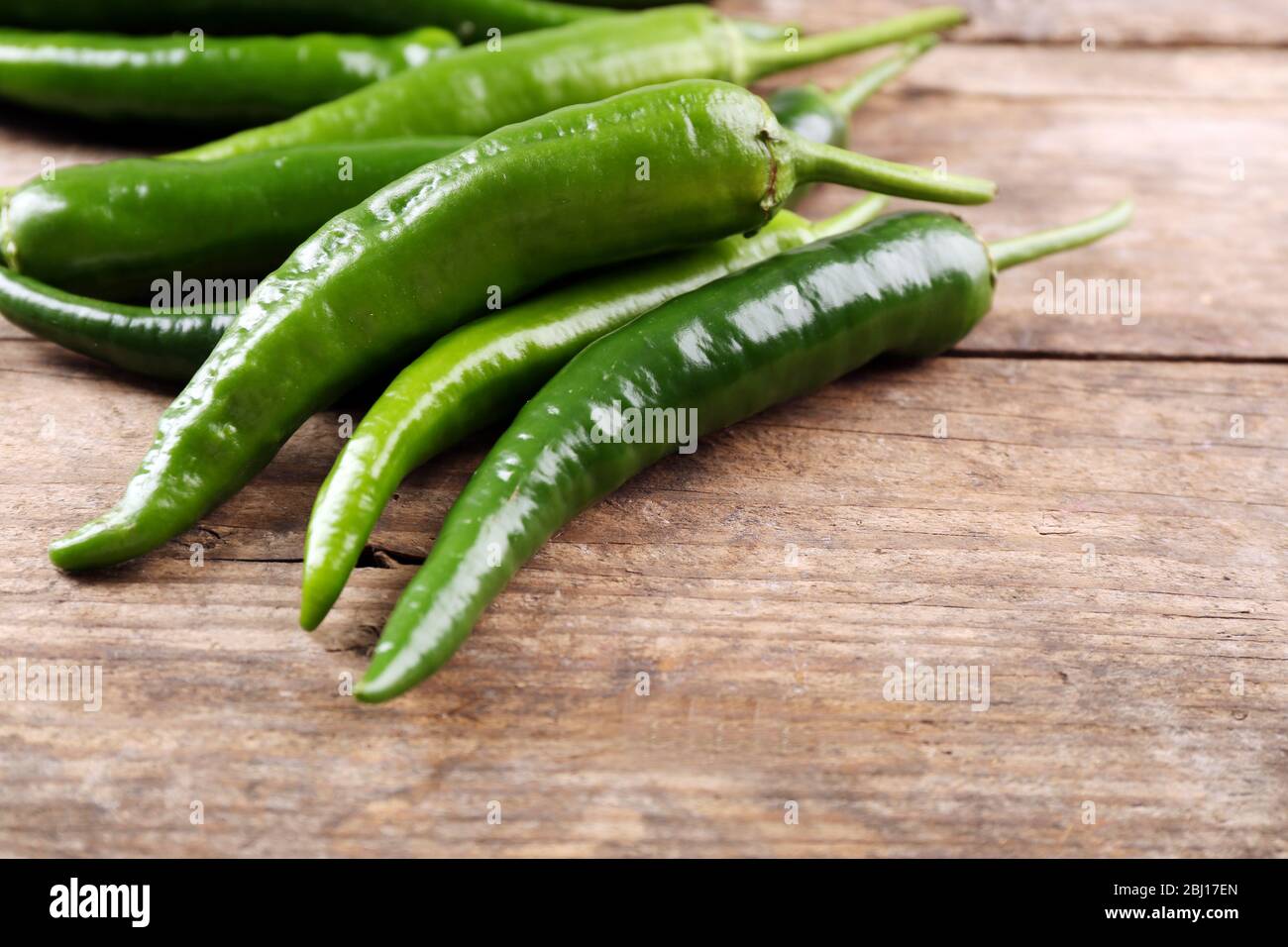 Green hot peppers on wooden table close up Stock Photo - Alamy