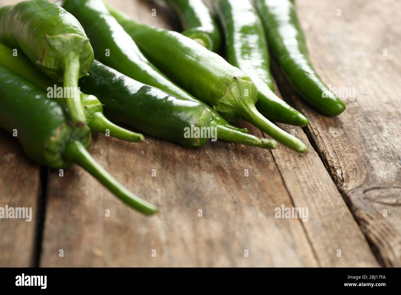 Green hot peppers on wooden table close up Stock Photo - Alamy