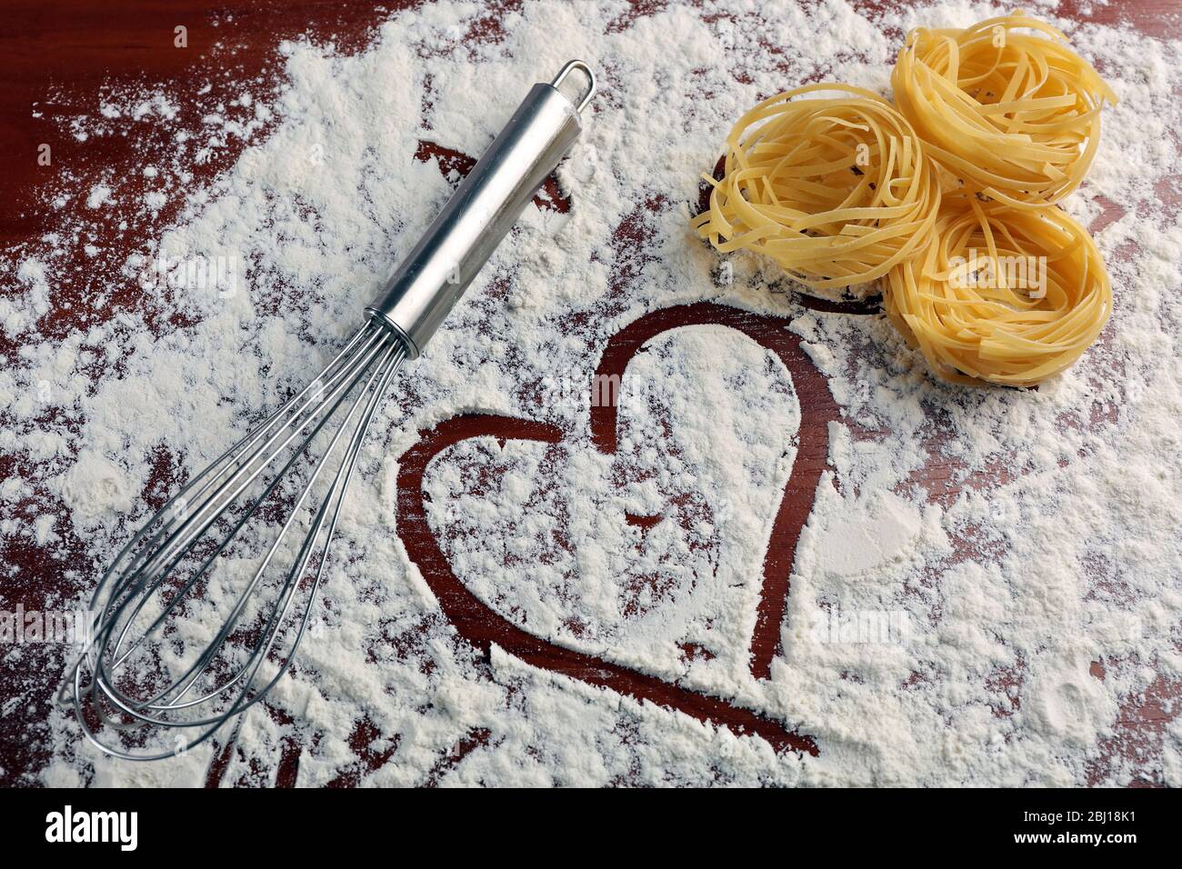 Row pasta with corolla on flour background Stock Photo - Alamy