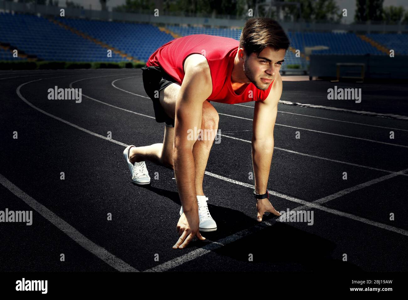 Runner in start position on stadium Stock Photo - Alamy