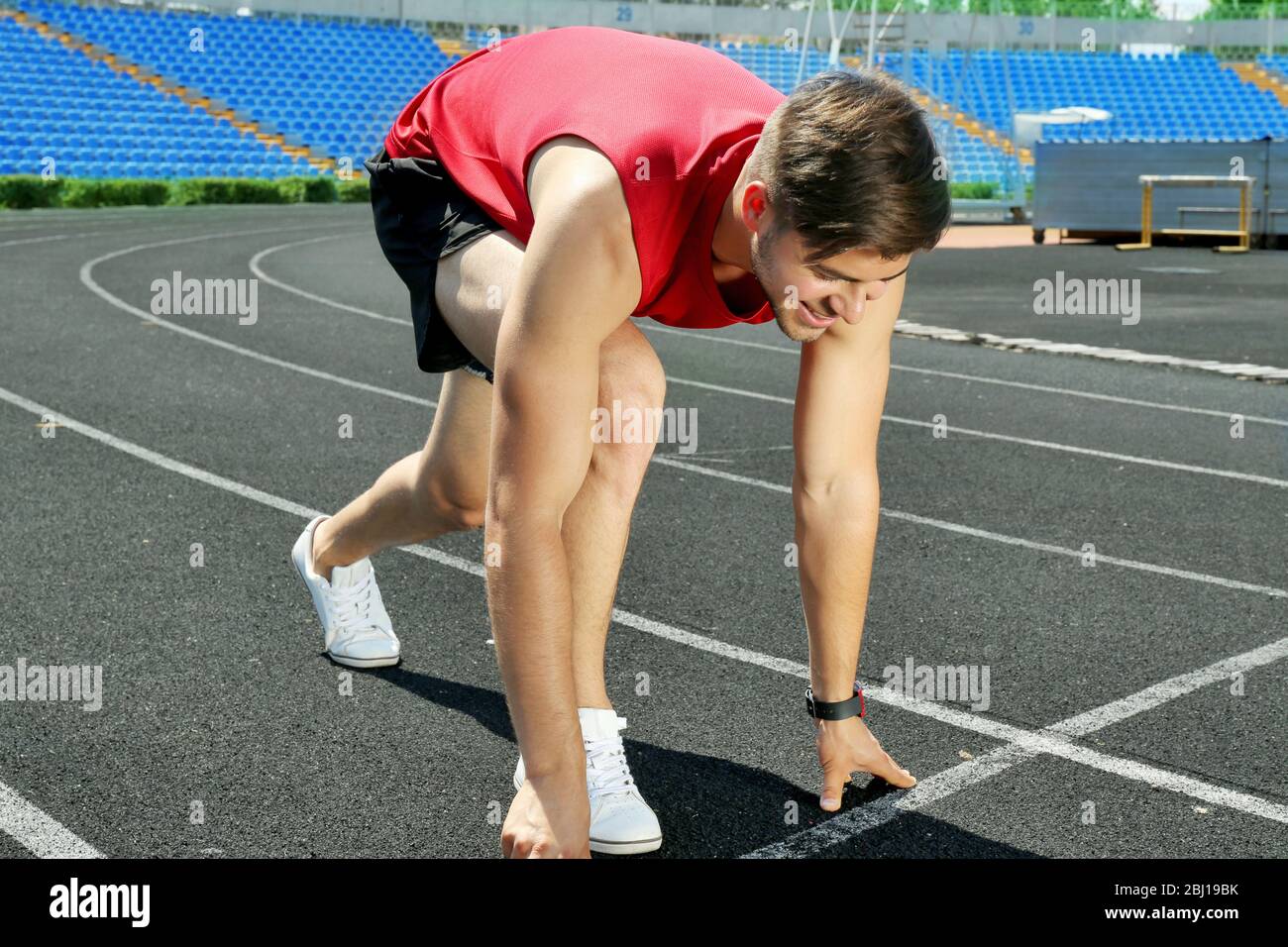 Runner in start position on stadium Stock Photo - Alamy