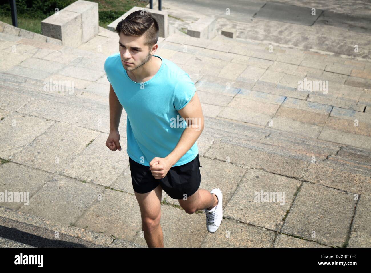 Young man jogging at stairs outdoors Stock Photo - Alamy
