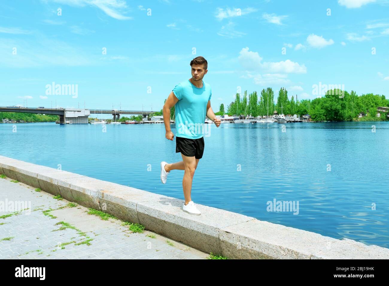 Young man jogging near river Stock Photo - Alamy