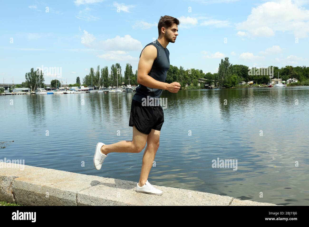 Young man jogging near river Stock Photo - Alamy