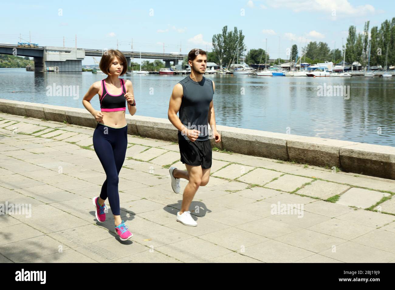 Young people jogging near river Stock Photo - Alamy