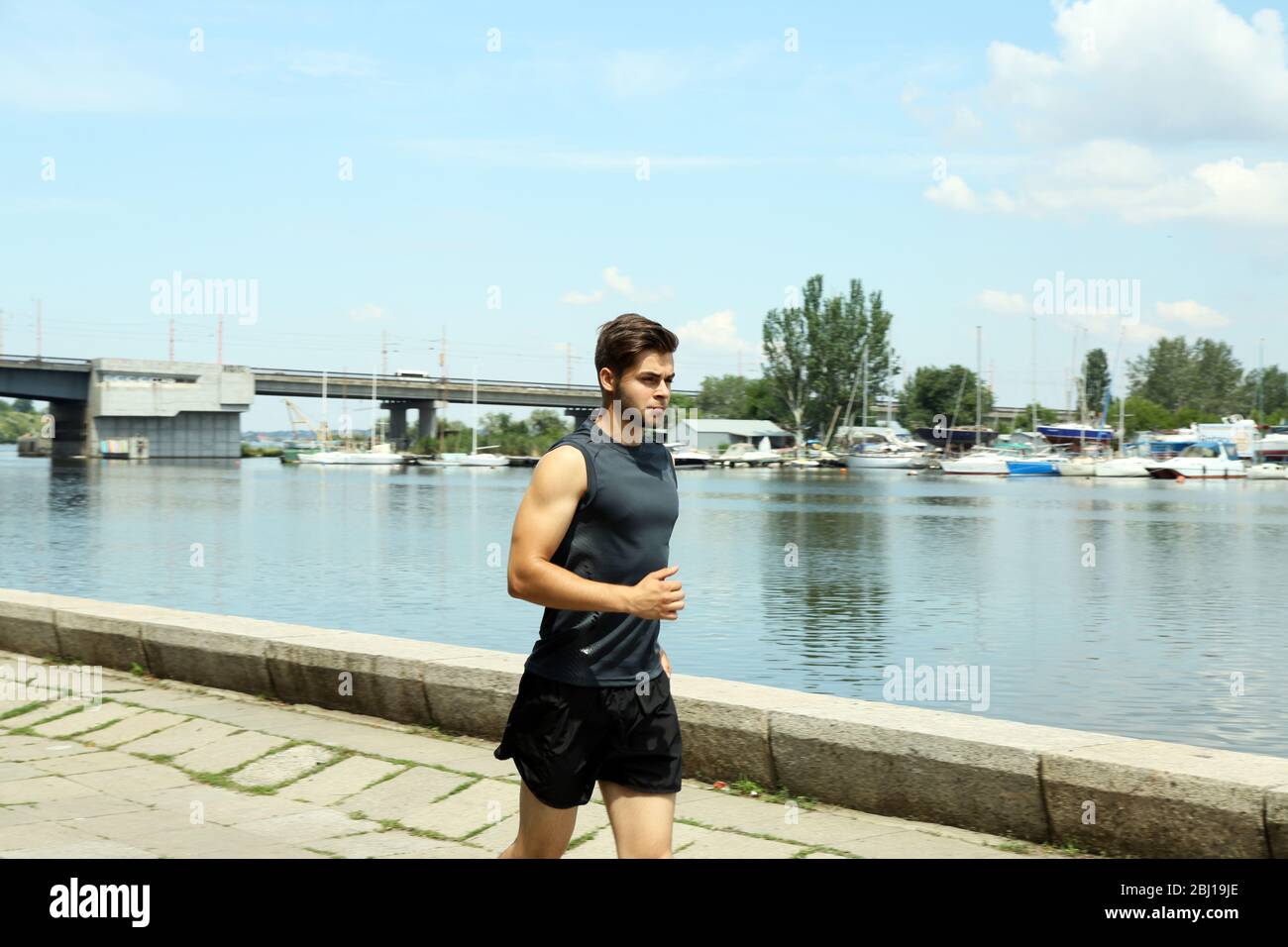 Young man jogging near river Stock Photo - Alamy