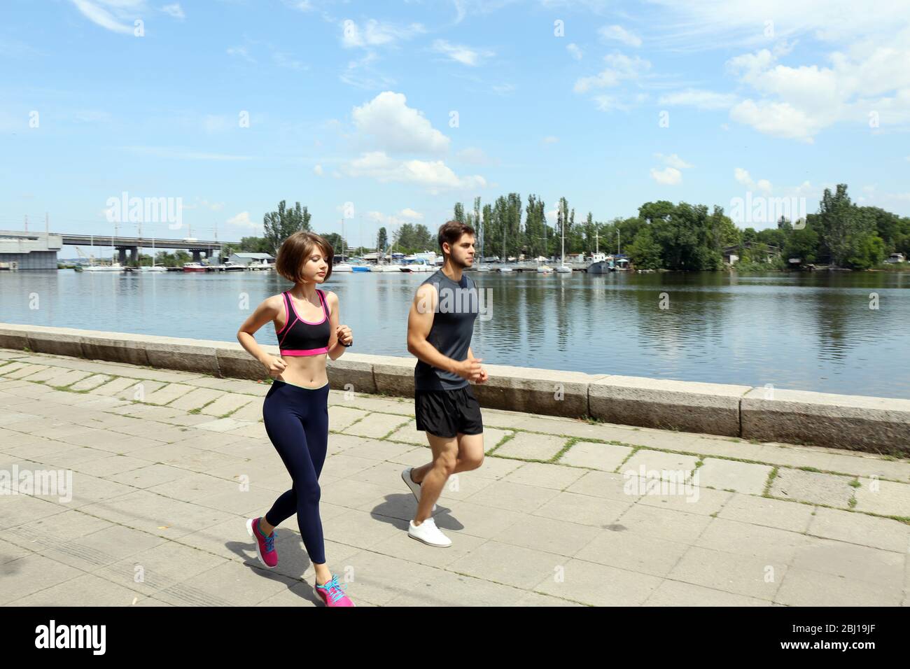 Young people jogging near river Stock Photo - Alamy