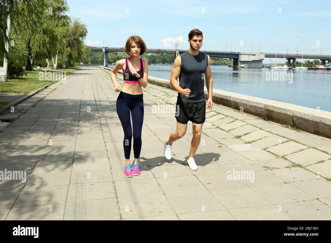 Young people jogging near river Stock Photo - Alamy