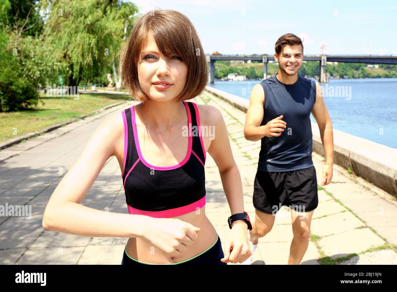 Young people jogging near river Stock Photo - Alamy