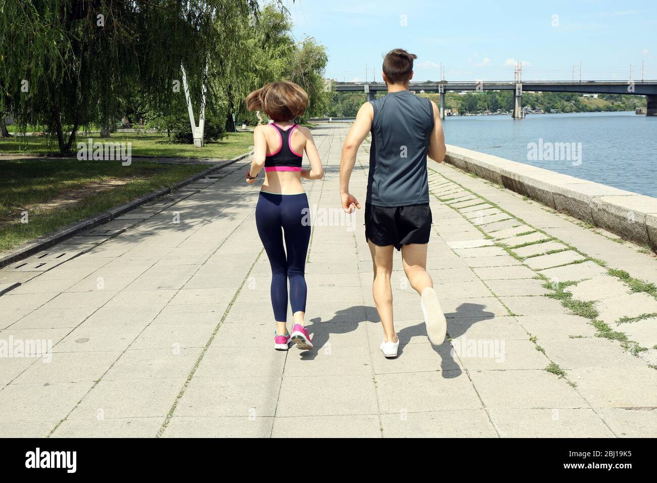 Young people jogging near river Stock Photo - Alamy