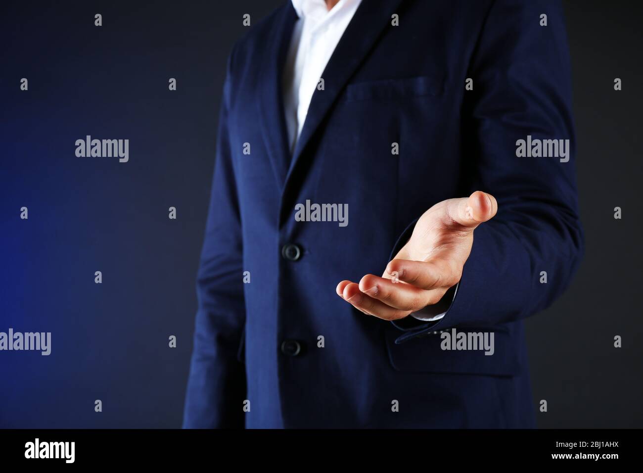 Businessman in suit introduce something on dark background Stock Photo ...