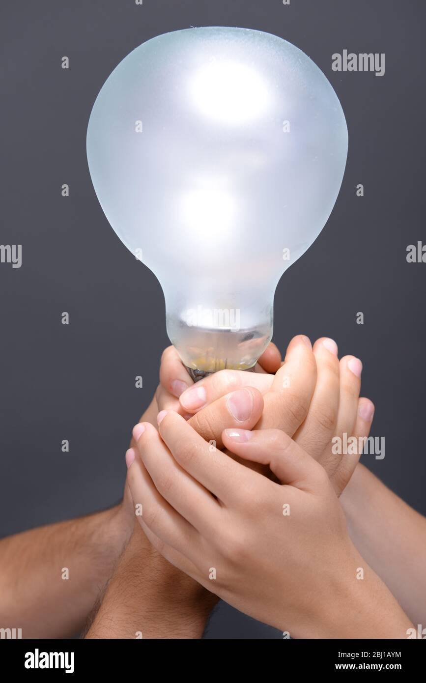 Light bulb in hands on grey background Stock Photo - Alamy