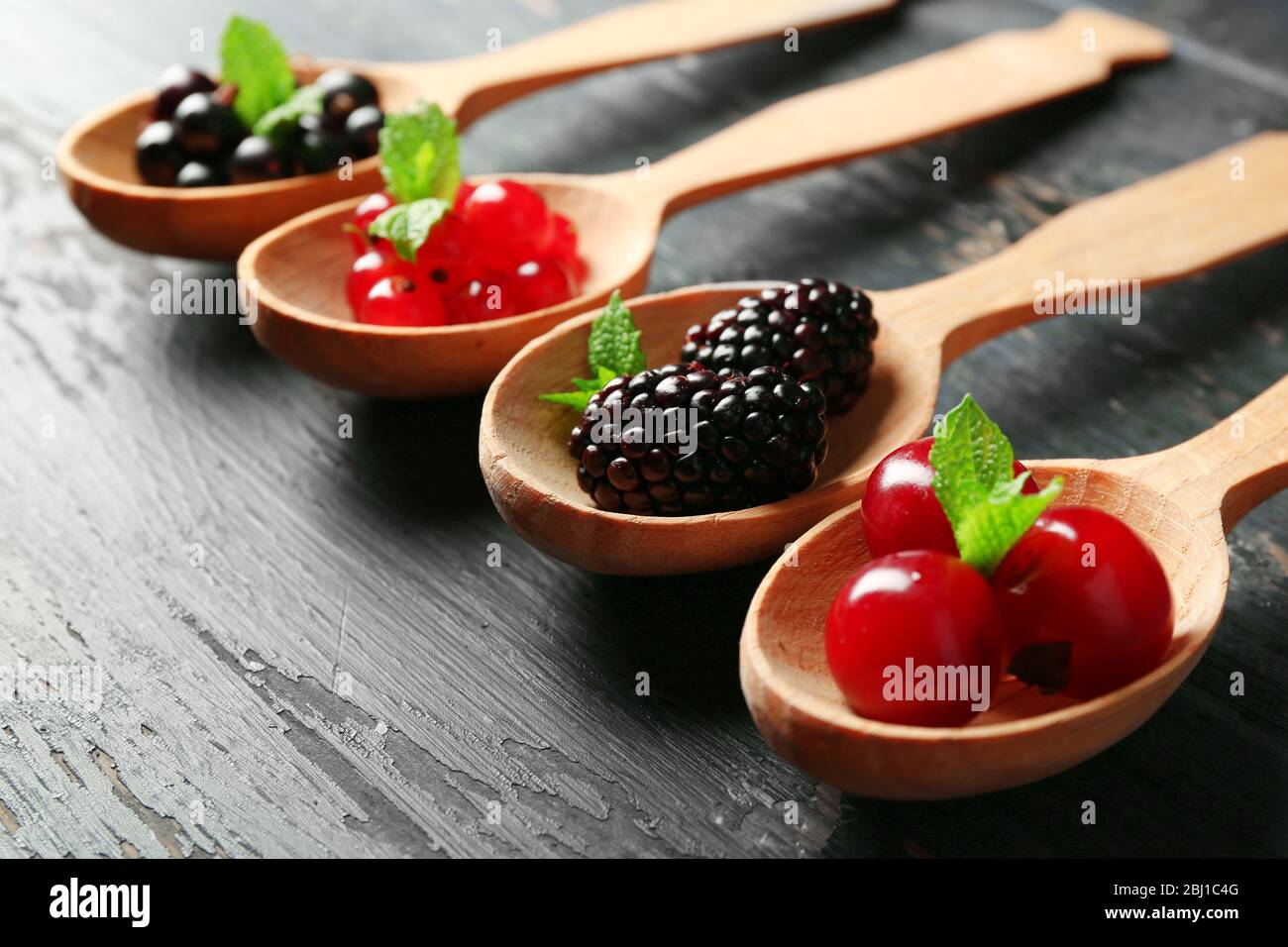 Forest berries in wooden spoons on color background Stock Photo - Alamy