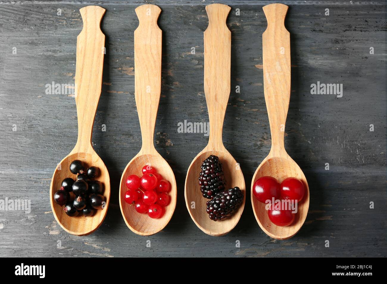 Forest berries in wooden spoons on color background Stock Photo - Alamy